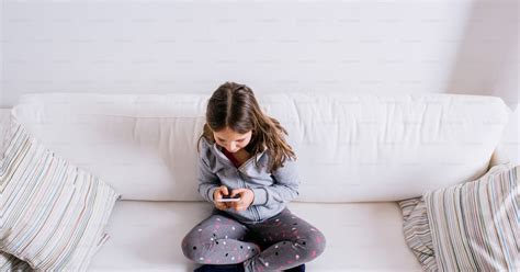 스마트폰으로 소파에 앉아 있는 어린 소녀 실내에서 노는 행복한 아이 사진 Unsplash의 베개 이미지