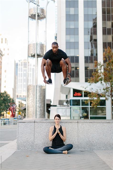 An Athletic Man Jumping Over A Woman Meditating By Stocksy Contributor Jakob Lagerstedt