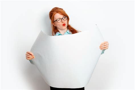 그녀의 손에 빈 캔버스를 들고 백인 빨간 머리 소녀와 얼굴에 찡그린 얼굴 배경에 회색 벽 공간을 복사합니다 모형 포스터와 아름 다운 젊은 사업가입니다 공란에 대한 스톡 사진