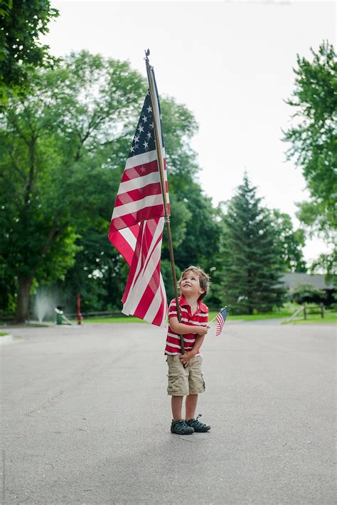 Boy Looks Up At The American Flag He Is Holding By Stocksy
