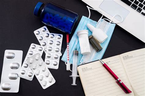 On A Black Background Is A Laptop Notebook Pen Pills Syringes Masks Drops Butyl Tablets