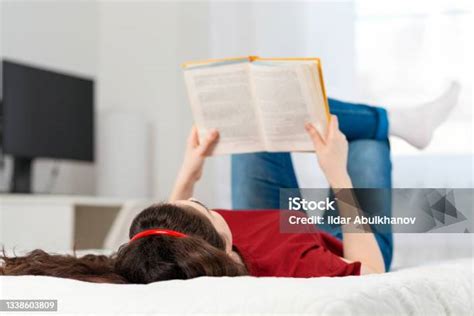 한 젊은 백인 여성이 침대에 누워 책을 읽고 있습니다 배경에 방의 흰색 인테리어 교육과 세계 도서의 날의 개념 가정의 방에 대한 스톡 사진 및 기타 이미지 Istock