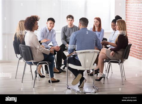 Group Of Businesspeople Sitting On Chair Having Discussion In Office