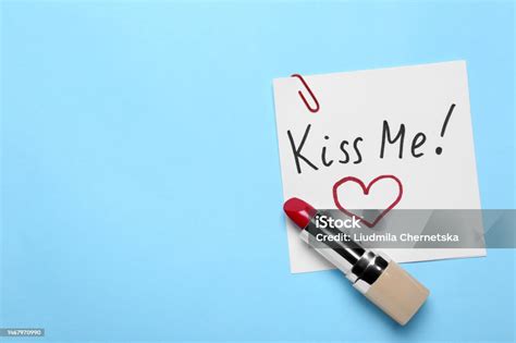 문구가 있는 카드 키스 미와 그려진 하트 밝은 파란색 배경에 립스틱 상위 뷰 텍스트를 위한 공간 접착식 메모지에 대한 스톡 사진
