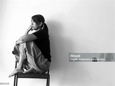 의자에 높은 무릎으로 앉아 스트레스 여자 그녀의 눈은 분실하고 혼란 화가 불행한 느낌 우울 장애 증후군 심각한 감정 배경의 왼쪽에 검은 색과 흰색 톤으로 Loking