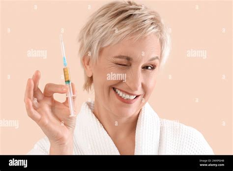Mature Woman With Beauty Injection Winking On Beige Background Closeup