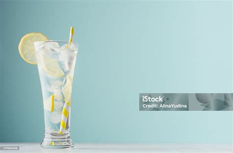 레몬 얼음 조각 소다 흰색 나무 테이블에 안개 유리에 노란색 줄무늬 빨대 파스텔 녹색 색상 배경과 수제 다이어트 투명 레모네이드