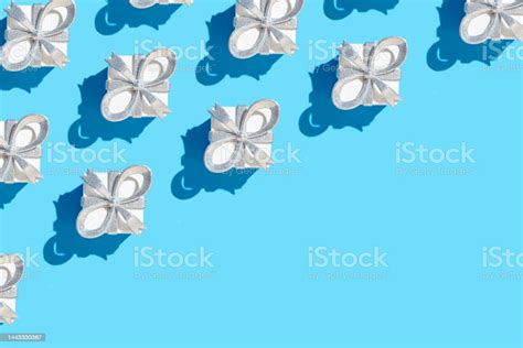 파스텔 블루 배경에 은색 활이 있는 반짝이는 흰색 선물 상자로 만든 창의적인 패턴 크리스마스 또는 생일 선물 개념입니다 휴일 테마 최소한의 스타일 2023년에 대한 스톡