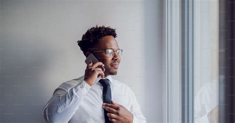 매력적인 아프리카계 미국인 사업가의 초상화는 창문 옆에 서서 동료와 전화 통화를 하는 동안 그것을 보고 있습니다 사진 Unsplash의 세르비아 이미지