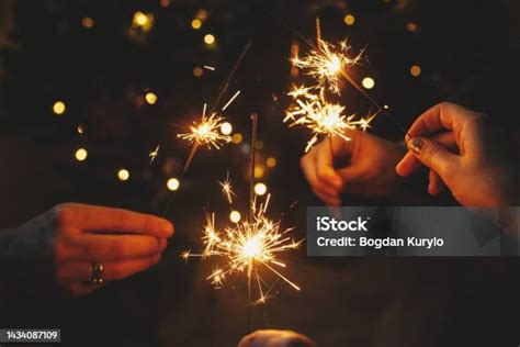 새해 복 많이 받으세요 어두운 방에서 크리스마스 불빛에 불꽃 놀이를 들고 손 대기 휴일 세련된 조명 나무의 배경에 손에 불타는