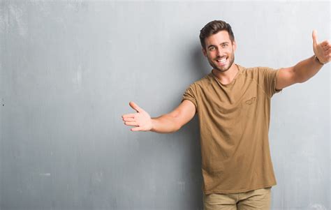 포옹에 대 한 두 팔을 벌려 웃 고는 카메라 보고 회색 그런 지 벽에 잘생긴 젊은 남자 명랑 식 수용 행복입니다 광대한에 대한 스톡 사진 및 기타 이미지 Istock