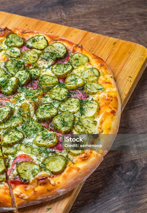 모짜렐라 치즈 살라미 베이컨 토마토 소스 신선한 딜 향신료 절인 오이를 곁들인 피자 나무 테이블 배경에 큰 딜 피자 작은 오이에