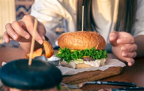 길거리 카페에서 햄버거를 먹고 있는 젊은 여자가 가까이 있다 감자 요리에 대한 스톡 사진 및 기타 이미지 감자 요리 거리