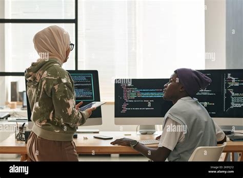 Two Young Intercultural It Engineers Discussing Ways Of Decoding Data