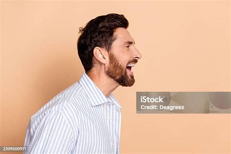 베이지색 배경에 즐거운 표정을 짓고 있는 줄무늬 셔츠를 입은 젊고 세련된 남자의 옆모습 40 44세에 대한 스톡 사진 및 기타