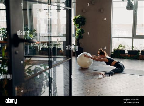 Sportive Flexible Woman With Hair In Bun Stretching Legs While Sitting