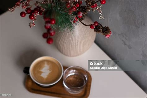 장식적인 붉은 가지가 있는 화병 근처의 물 한 잔과 함께 커피 라떼 또는 카푸치노 한 잔 내부 아늑한 0명에 대한 스톡 사진 및 기타 이미지 Istock