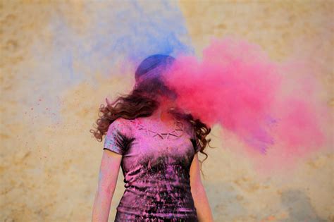 사막에서 분홍색과 파란색 건조 홀리 파우더와 함께 즐거운 시간을 보내는 긴 물결 모양의 머리를 가진 젊은 갈색 머리 소녀 감정에