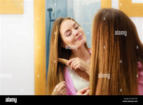 Woman Combing Brushing Her Long Smooth Hair In Bathroom Looking In