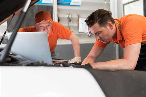 차고에서 일하는 두 명의 기계공 자동차 수리 서비스에서 자동차 후드 아래에서 전문 정비사 검사 수리 및 유지 보수 그룹 자동차 서비스 개념 25 29세에 대한 스톡 사진 및