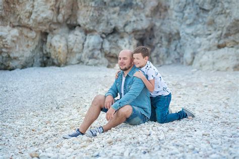 귀여운 아들 소년 십 대와 함께 해변 바다 쪽에 앉아 파란 모자에 청바지 남자를 입고 잘생긴 대담한 세련 된 및 예쁜 영어 불독