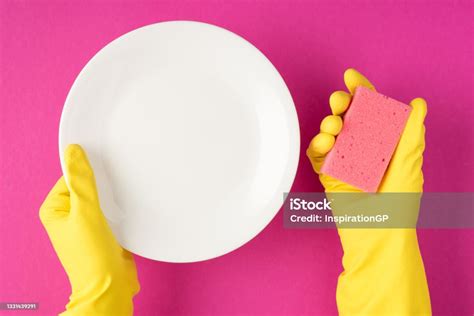 흰색 깨끗한 접시와 빈 공간이있는 고립 된 분홍색 배경에 분홍색 수색 패드를 들고 노란색 고무 장갑에 손의 상단 보기 사진 가사 집안일에 대한 스톡 사진 및 기타 이미지