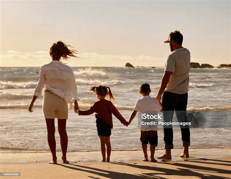 해변에서 자유 시간을 즐기는 아들과 딸을 둔 백인 부모의 뒤로 어린 소년과 소녀는 주말에 손을 잡고 어머니와 아버지와 유대 관계를 맺습니다 일몰을 보는 가족 가까운에 대한