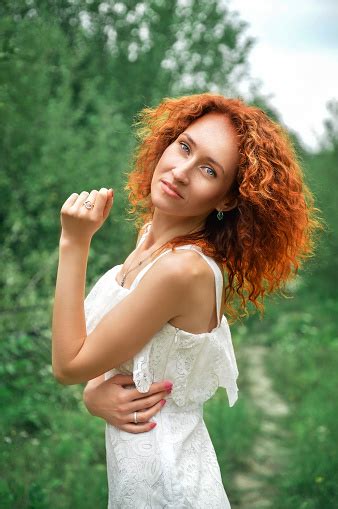 닫아 녹색 공원 중 흰색 레이스 드레스에 아름다운 빨간 머리 소녀 자연스러운 메이크업을 한 얼굴 회색 눈의 몽상적인 표정이 카메라를 향하고 있습니다 가냘픈에 대한 스톡 사진
