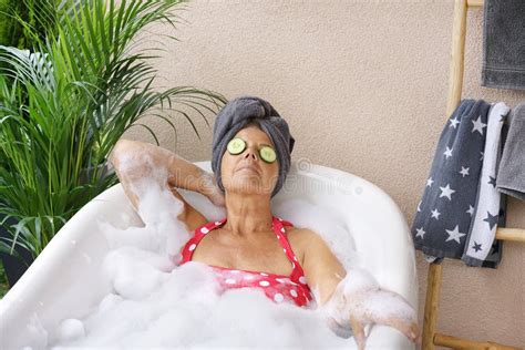 Woman With Cucumber Slices On Her Eyes Taking A Bath In A Bathtub In