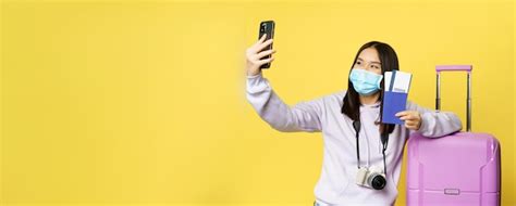 스마트폰으로 사진을 찍는 여행 가방 근처에서 여권과 티켓으로 셀카를 찍는 행복한 아시아 여성 무료 사진