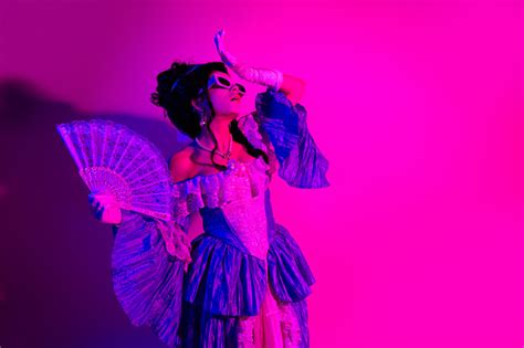 바로크 의상을 입은 젊은 여성과 생생한 자외선 조명에 선풍기를 들고 역사적인 우아함과 현대적인 네온 미학을 병치합니다 25 29세에 대한 스톡 사진 및 기타 이미지 Istock
