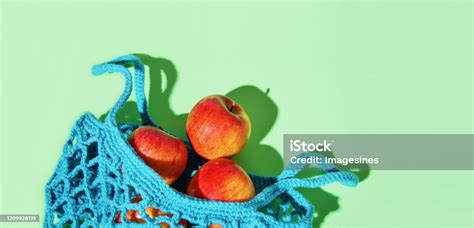 재사용 가능한 쇼핑 문자열 가방 신선한 사과와 오픈 그물 가방 녹색 그림자 파노라마 배경에 과일이있는 파란색 메쉬 쇼핑 백 폐기물 제로 친환경 쇼핑객 및 생태 개념 플라스틱