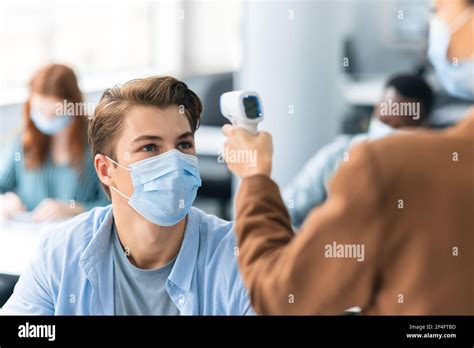 Teacher With Contactless Thermometer Gun Measuring Temperature Of Male Babe Stock Photo Alamy