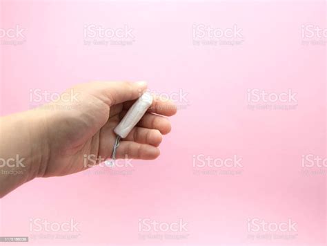 여자의 손은 분홍색 배경에 흰색 깨끗한 탐폰을 들고있다 생리 기간 여성의 건강을 걱정하십시오 개념에 대한 스톡 사진 및 기타