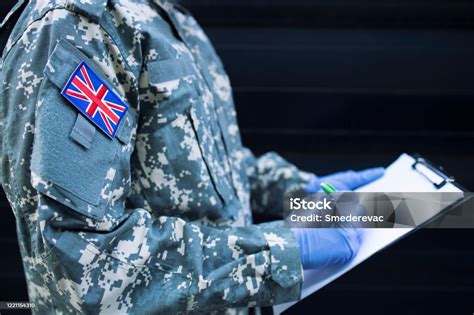 고무 장갑을 착용한 위장 복을 입은 영국 군인은 병원 문 앞에서 누가 들어오거나 나가는지 통제하는 마스크를 쓰고 있다 코로나