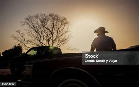 일몰 동안 빈티지 자동차에 서있는 카우보이 모자를 쓴 성인 남성의 초상화 일몰에 대한 스톡 사진 및 기타 이미지 일몰 차 남자 Istock