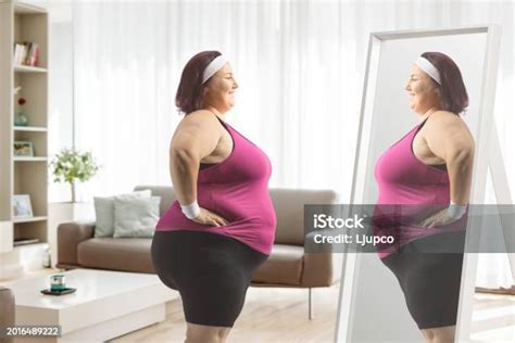 플러스 사이즈 운동복을 입은 여성이 거울에 비친 자신의 모습을 보고 있습니다 35 39세에 대한 스톡 사진 및 기타 이미지 35 39세 가정의 방 거울 Istock