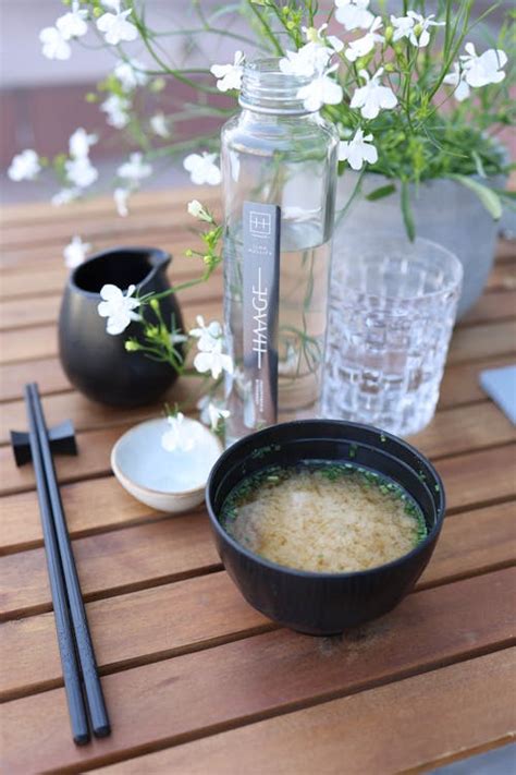 검은 그릇 고요한 분위기 꽃 장식 동양식기 된장국 레스토랑 맛있는 식사 목조 테이블 문화 요리 문화식사 물병 미니멀리스트 스타일 미소시루 수직 쐈어