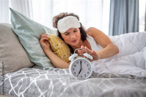 Fotka „woman Lying In Bed Turning Off An Alarm Clock In The Morning At