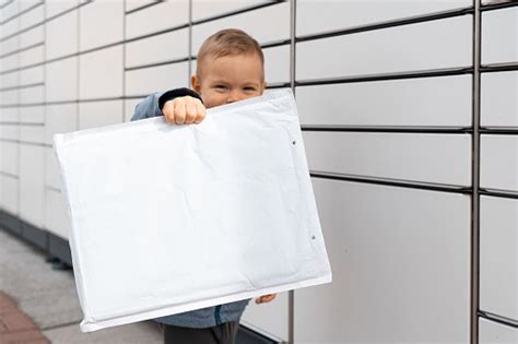 소포 배달 사물함이있는 픽업 포인트 소포가있는 어린이 비접촉식 팩 배달 아이 소포 포장을 보내거나 받기 위하여 셀프 서비스 소포 맨끝 기계를 사용하는 소년 2 3 살에 대한