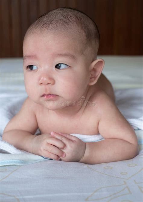 Soft Focus On Adorable Naked Curious Infant Baby Lay On Stomach On The Bed After Taking A Bath