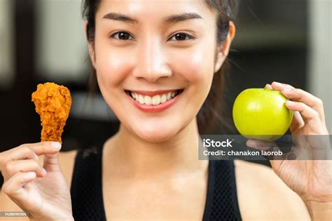 사과와 프라이드 치킨 정크 푸드를 먹는 운동복을 입은 아름다운 여성은 고칼로리 음식과 건강 위험 건강에 해로운 음식을 가진 배