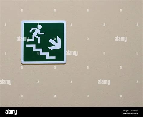 Green Sign Down The Stairs On A Bright Wall Direction To The Emergency Exit Stock Photo Alamy