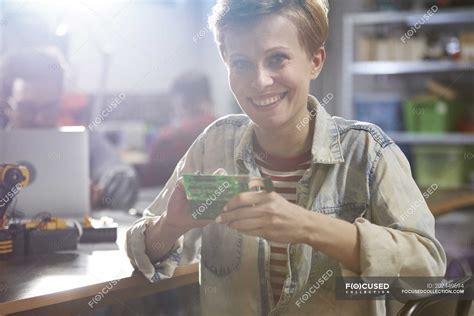 Portrait Smiling Female Engineer Assembling Circuit Board In Workshop