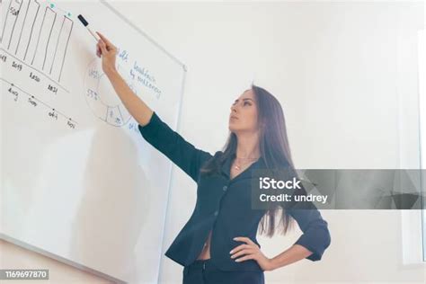 화이트 보드에 프리젠 테이션을 보여주는 강의를주는 여성 교사 가리키기에 대한 스톡 사진 및 기타 이미지 가리키기 강사 개인 지도 교사 Istock