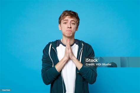함께 캐주얼에 절망적 인 젊은 남자의 초상화 스튜디오에서 파란색 벽 배경에 고립 된 기도하는 함께 손을 잡고 사람들은 진심으로 감정 라이프 스타일 개념입니다 복사 공간을