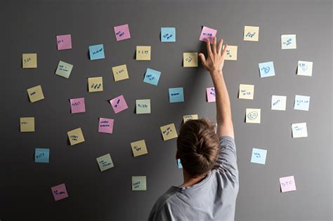 사무실에있는 사람은 종이 스티커를 들고 벽에 붙입니다 작업 계획 노트에 대한 스톡 사진 및 기타 이미지 노트 메모장 모임