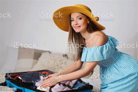 파란색 드레스와 노란 모자 포장 가방에 쾌활 한 젊은 아름 다운 여 자가 여행 준비 하기 가득 찬에 대한 스톡 사진 및 기타