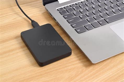 external backup hard disk drive connected to laptop on wooden table