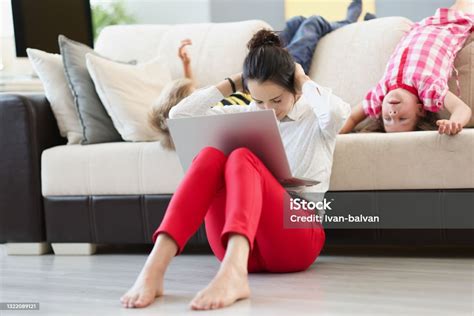 아이들과 함께 있는 젊은 여자 와 함께 바닥에 앉아 노트북에 그녀의 무릎과 그녀의 귀를 덮고 정서적 탈진에 대한 스톡 사진 및 기타 이미지 Istock